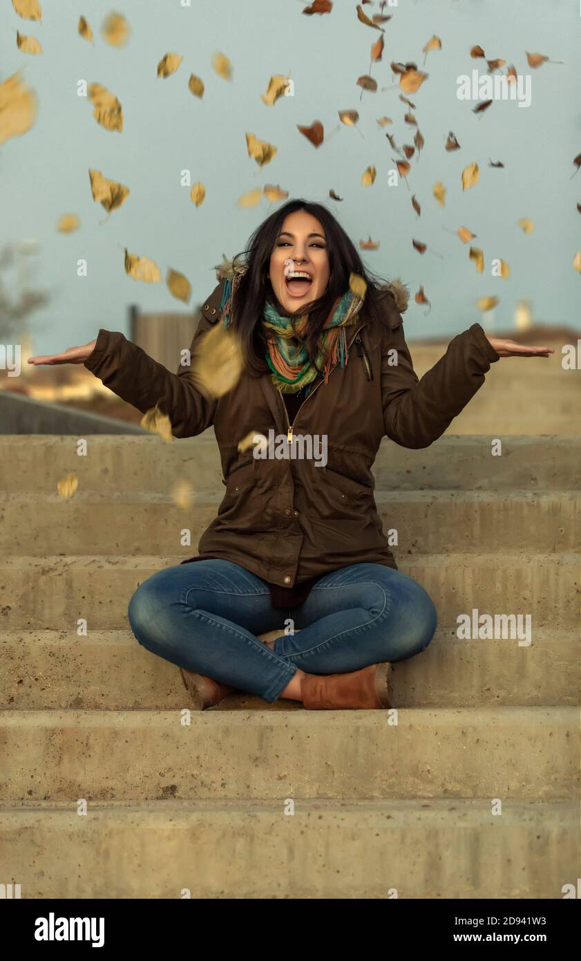 Funny girl sitting on a stairs with fall leaves over her Stock Photo ...