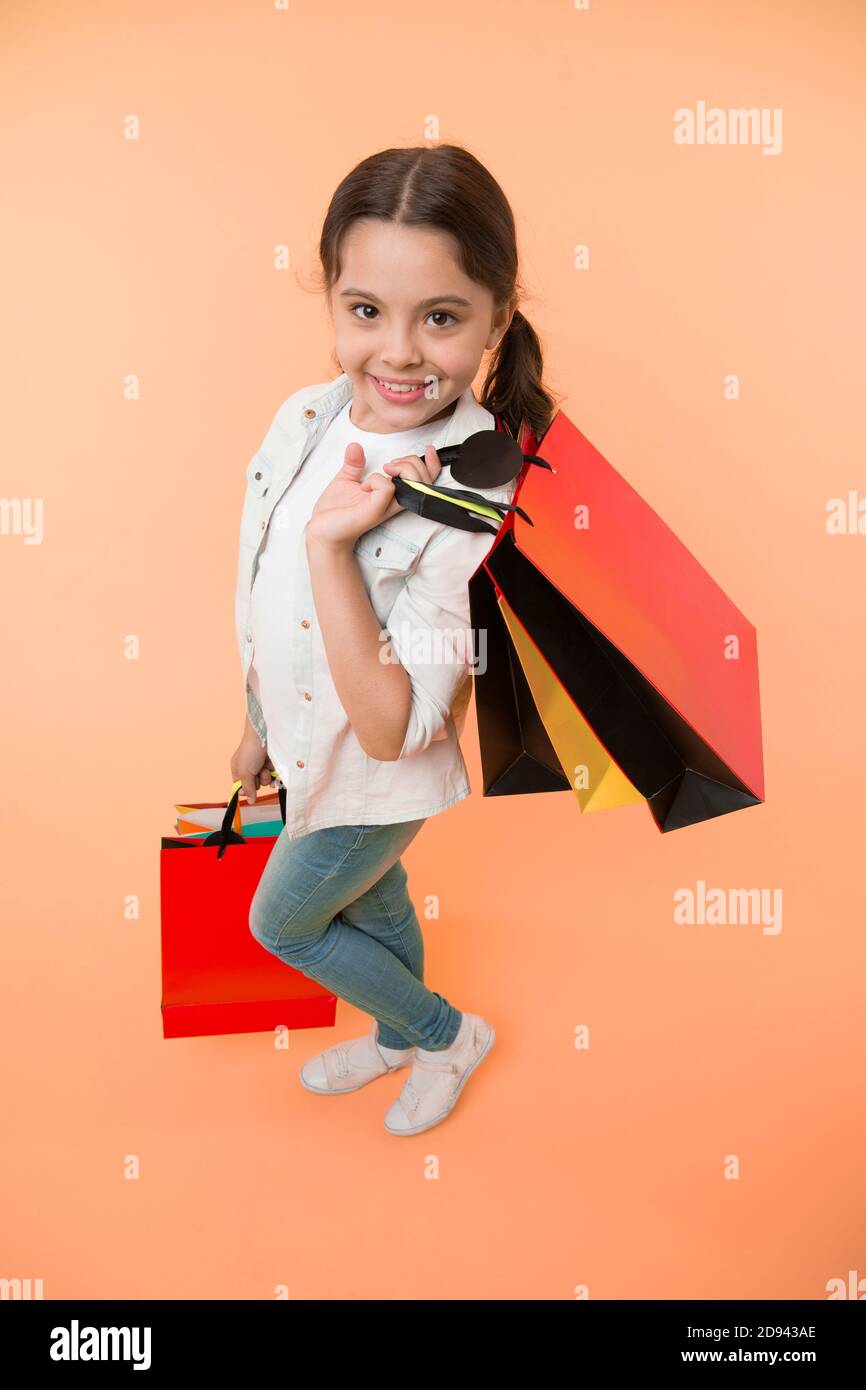 Happy child hold shopping bags on yellow background. Little shopaholic ...