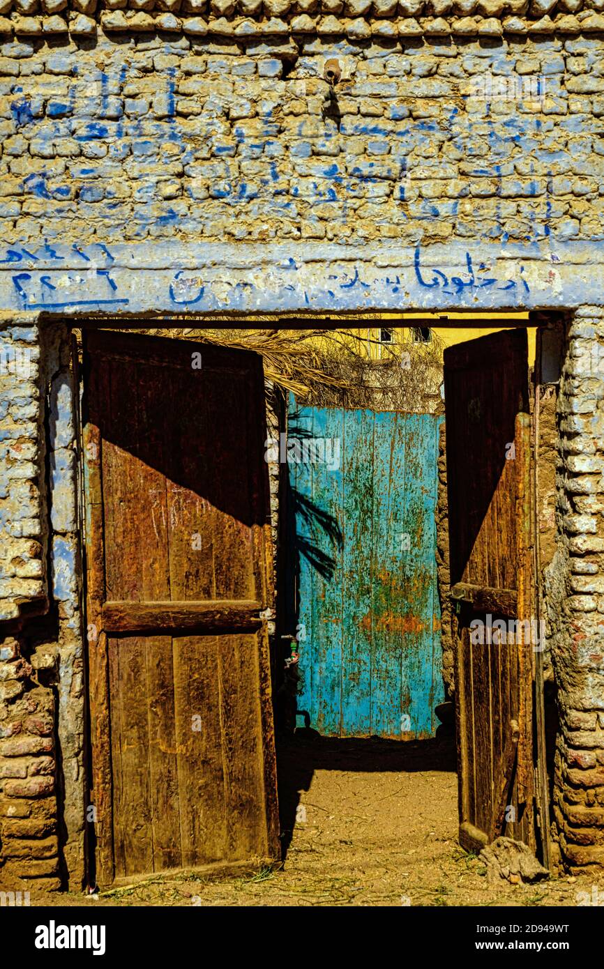 Dilapidated brickwork and wooden doors leading to an inner courtyard of ...
