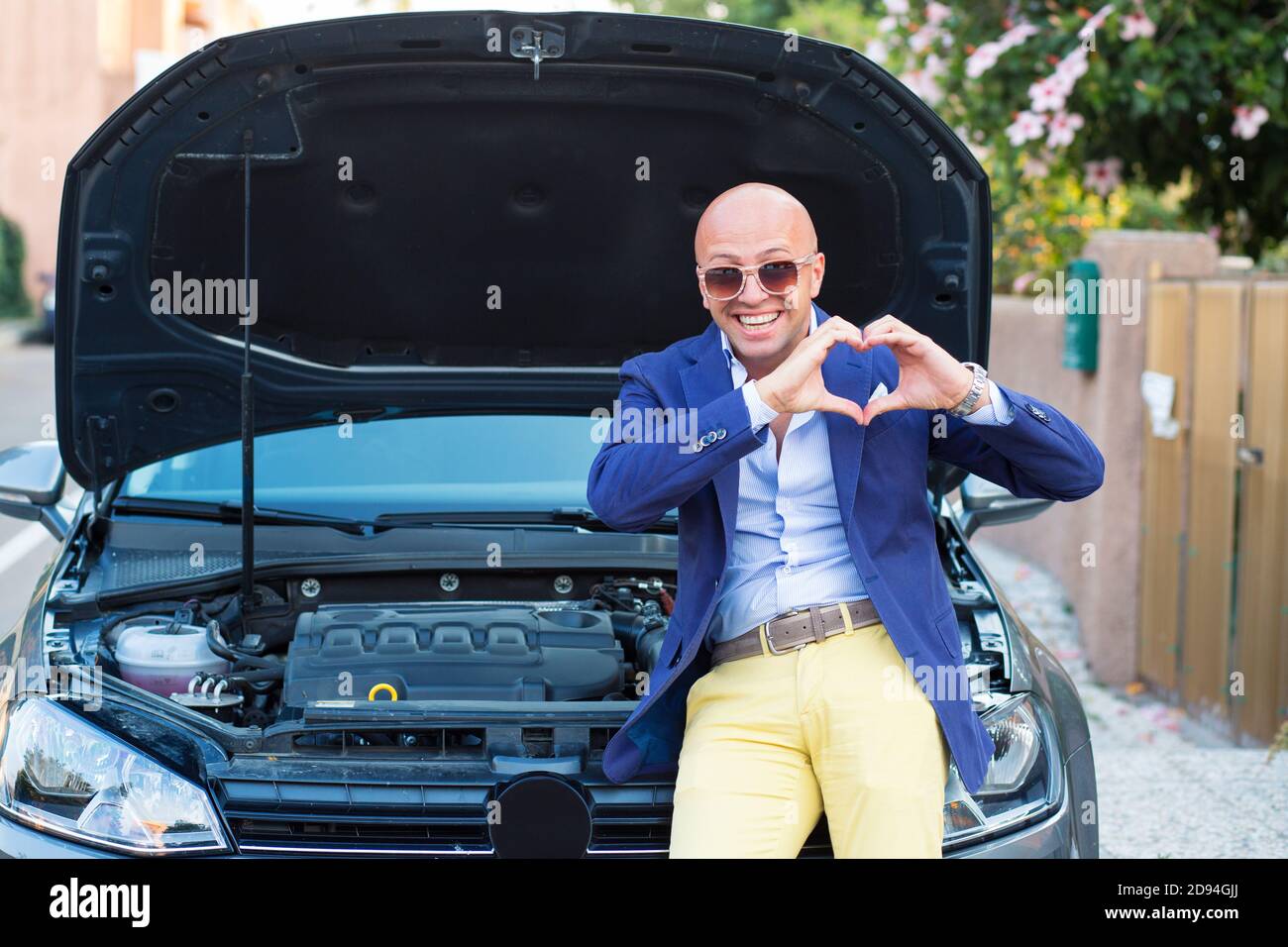 I love my engine car. Handsome man showing heart hand gesture standing ...
