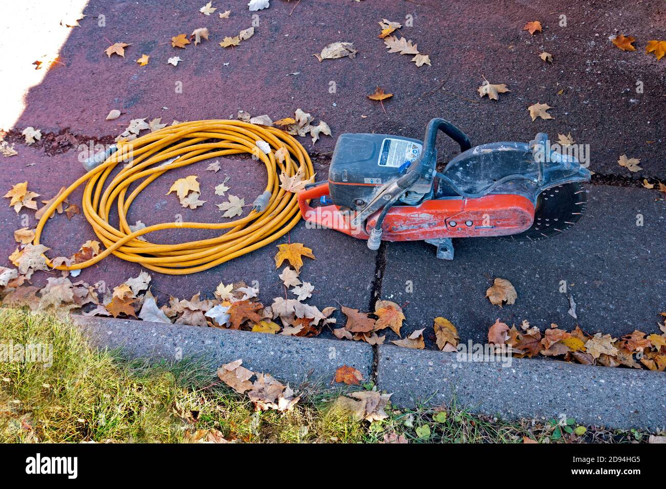 A cement saw with a wound yellow electrical cord in the gutter. St Paul ...