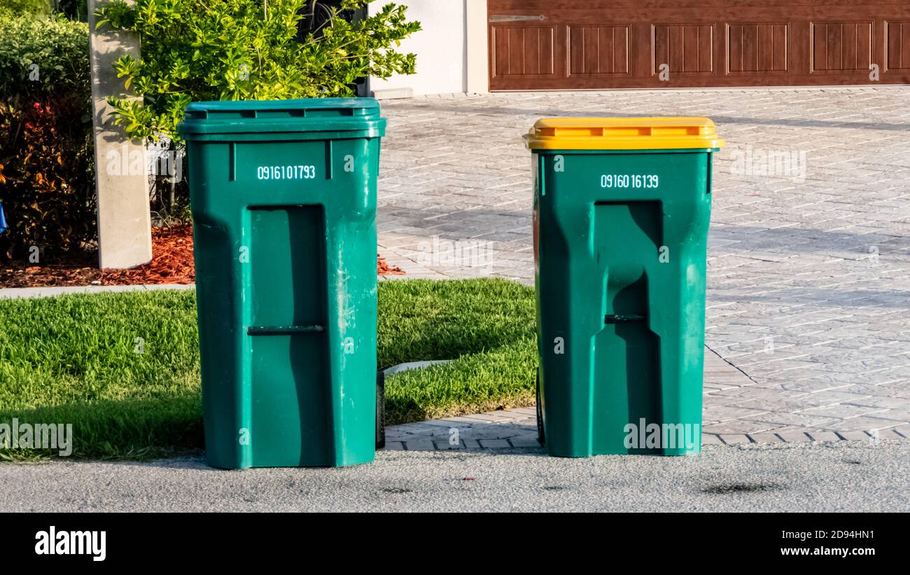 Green and yellow waste management garbage cans at the curb for trash ...
