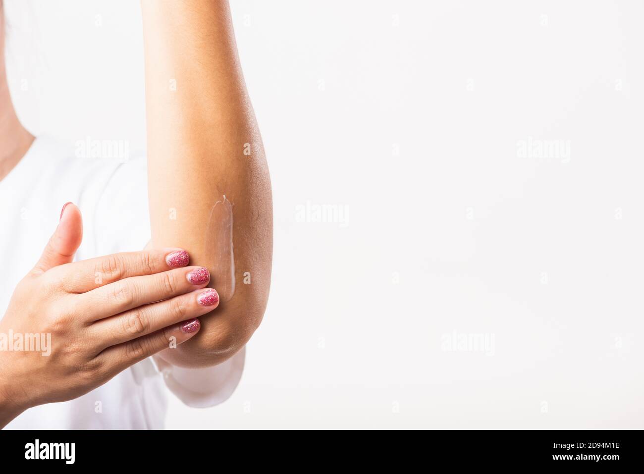 Closeup young Asian woman applies lotion cream on her elbow, studio ...