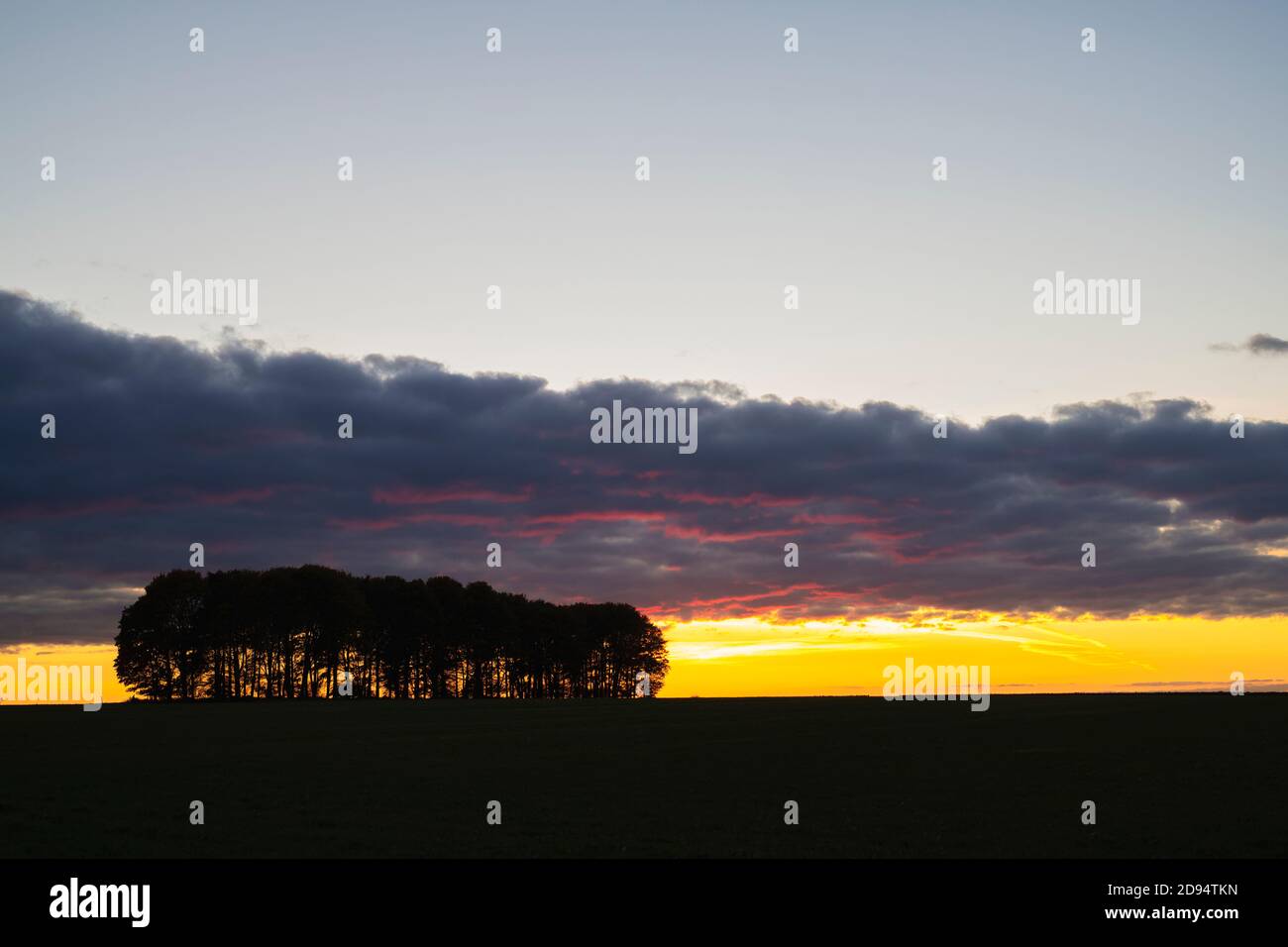 Band of rain clouds at sunset over the cotswold countryside with trees ...