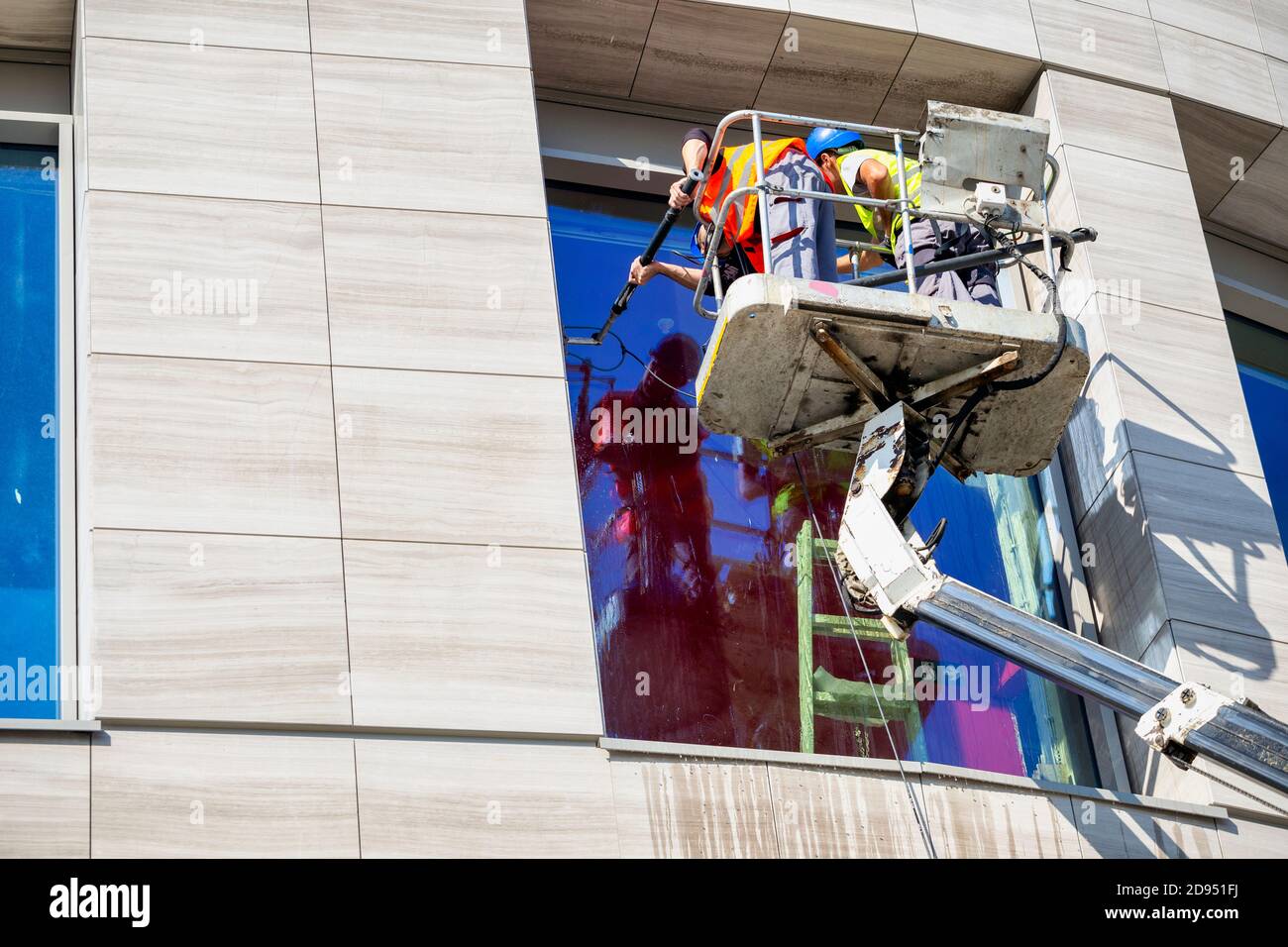 Workers in elevated work platform cleaning windows on height, cleaning ...