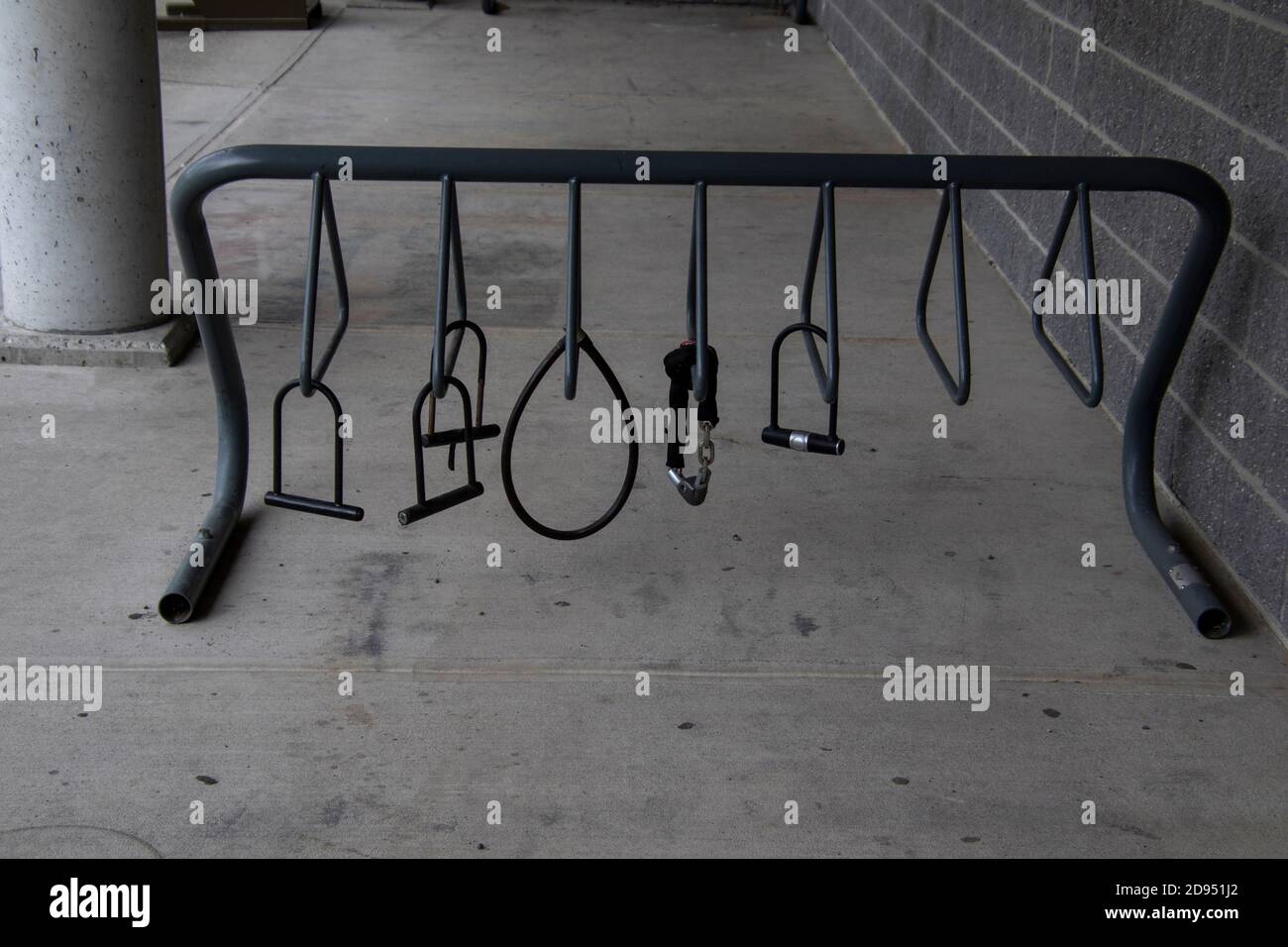 A bike rack attached to a cement pad next to a brick building with bike ...