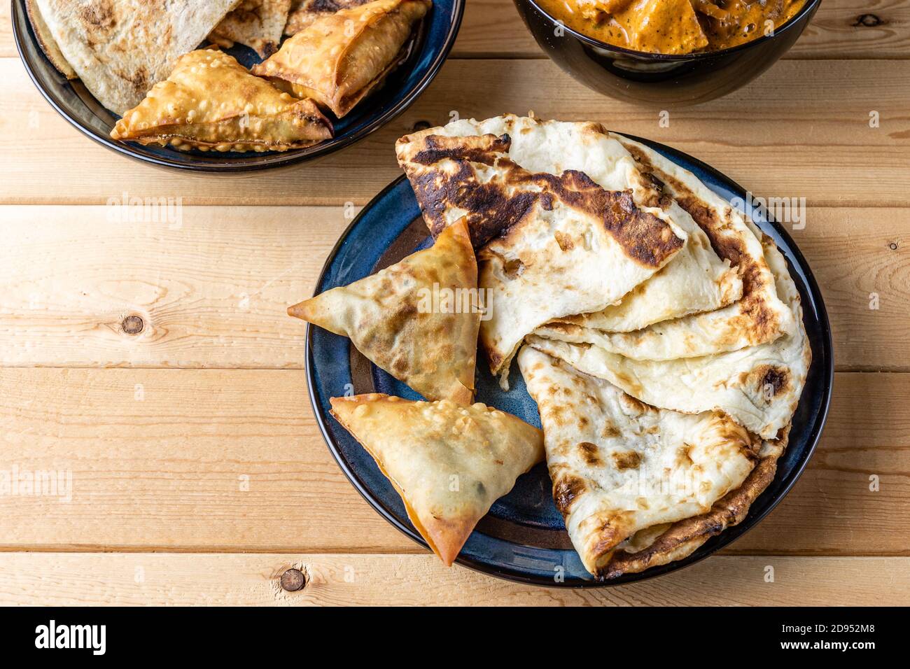 Indian snacks samosa garlic naan bread butter chicken on wooden table ...
