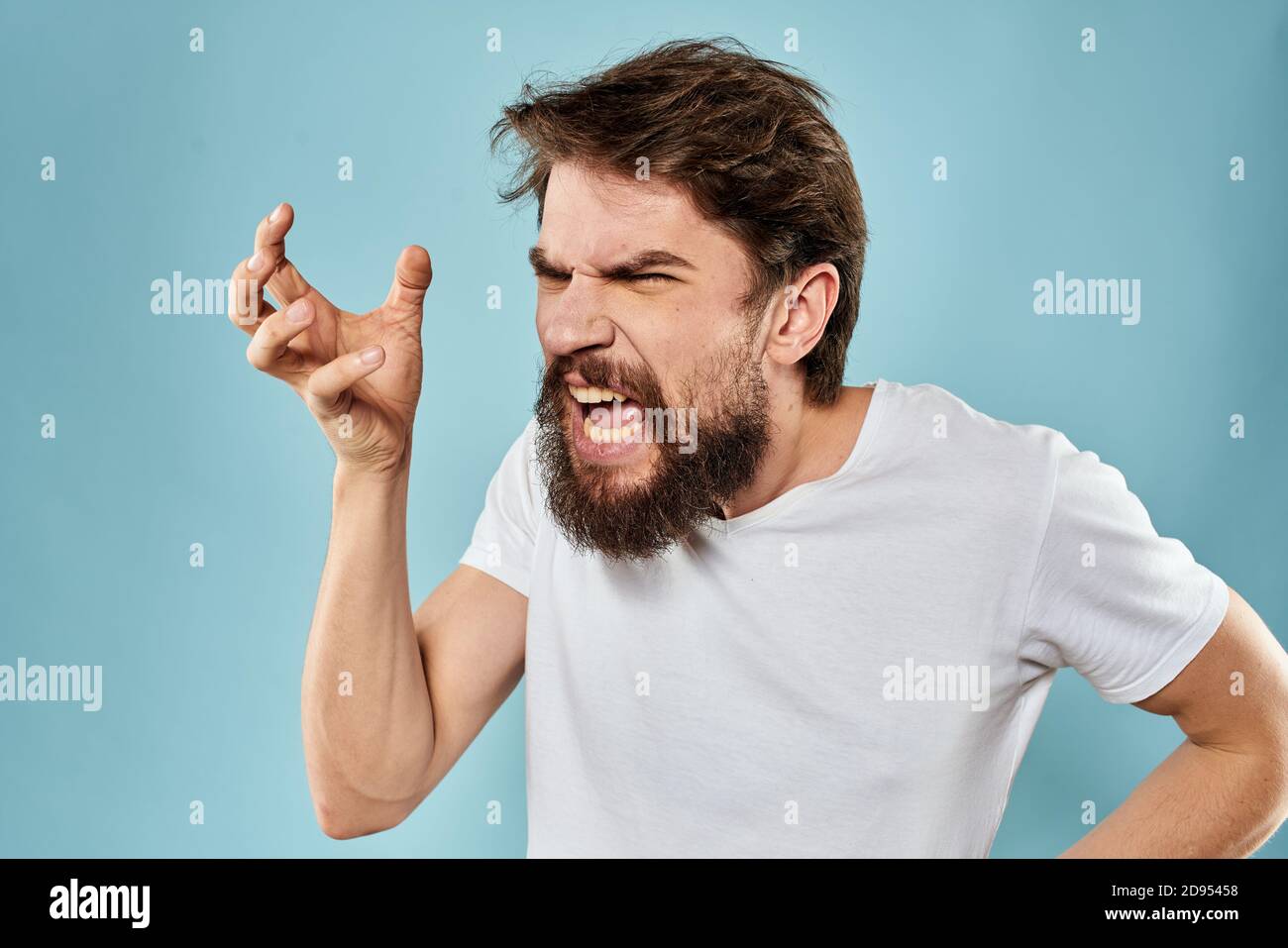 Bearded man in white T-shirt emotions gestures with hands displeased ...