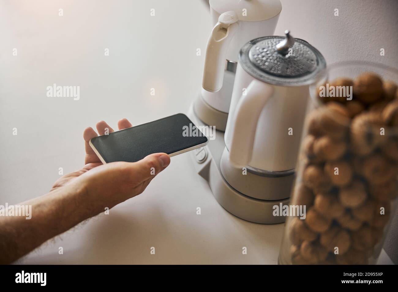 Person turning on a smart kettle with a help of a phone Stock Photo - Alamy
