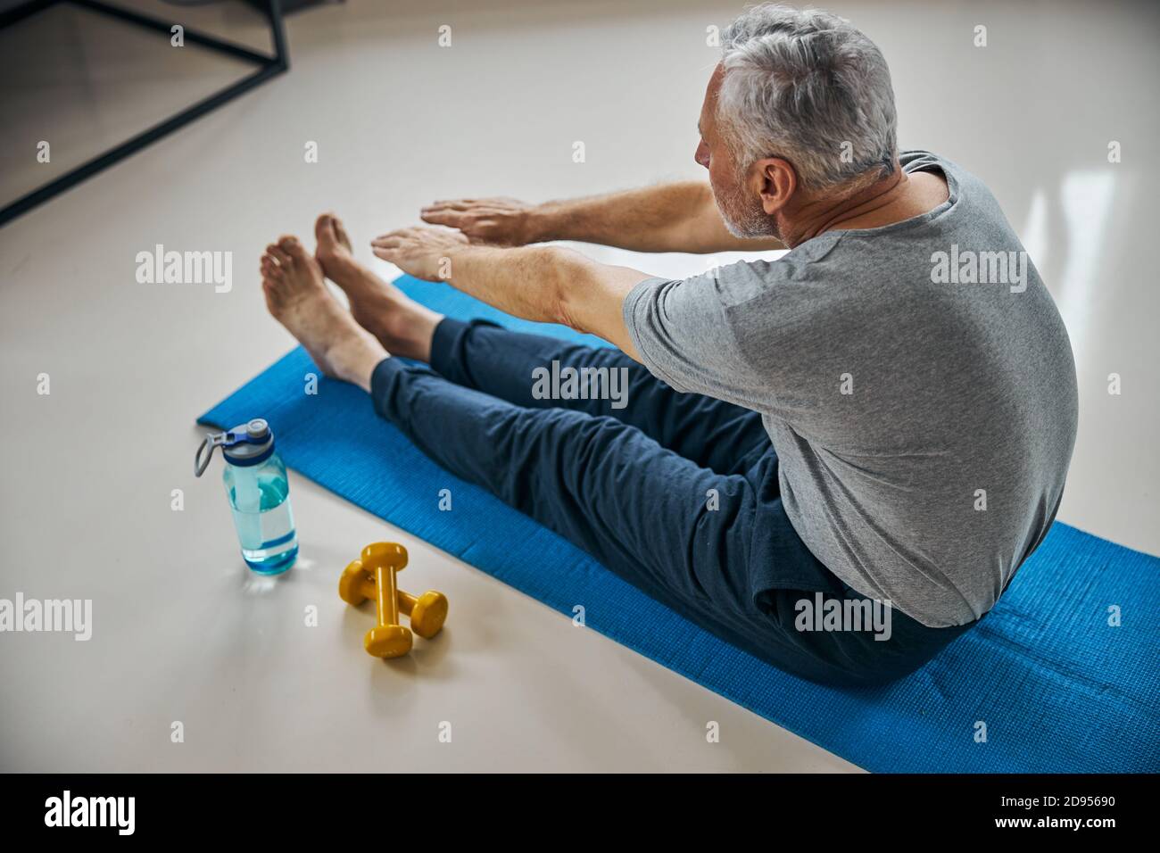 Fit senior citizen stretching towards his toes while exercising Stock ...