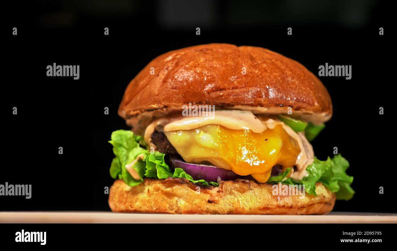 Craft burger is cooking on black background. Consist: sauce salsa ...