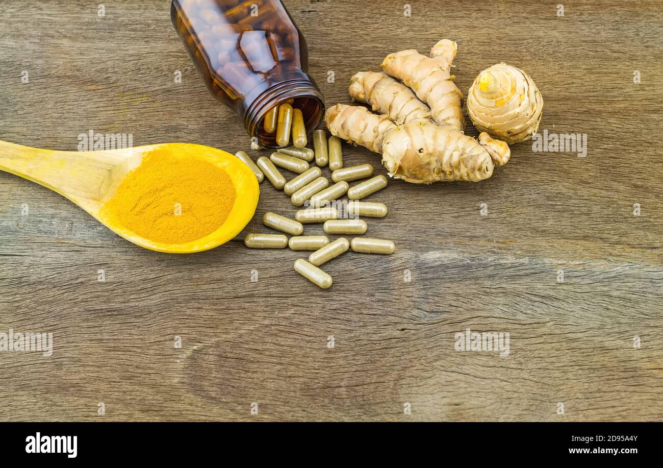 Turmeric herbal capsules in black bottle ,fresh turmeric root and ...