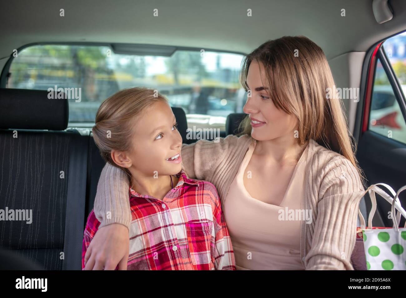 Happy mom hugging her daughter on backseat of car Stock Photo - Alamy