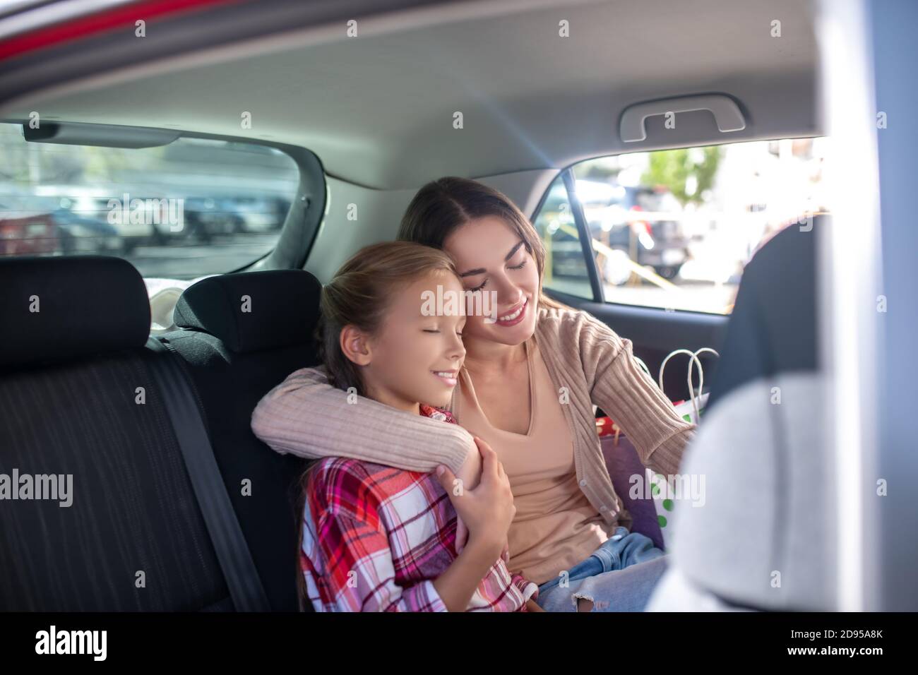 Mom hugging her daughter, sitting cheek to cheek on backseat of car Stock Photo - Alamy
