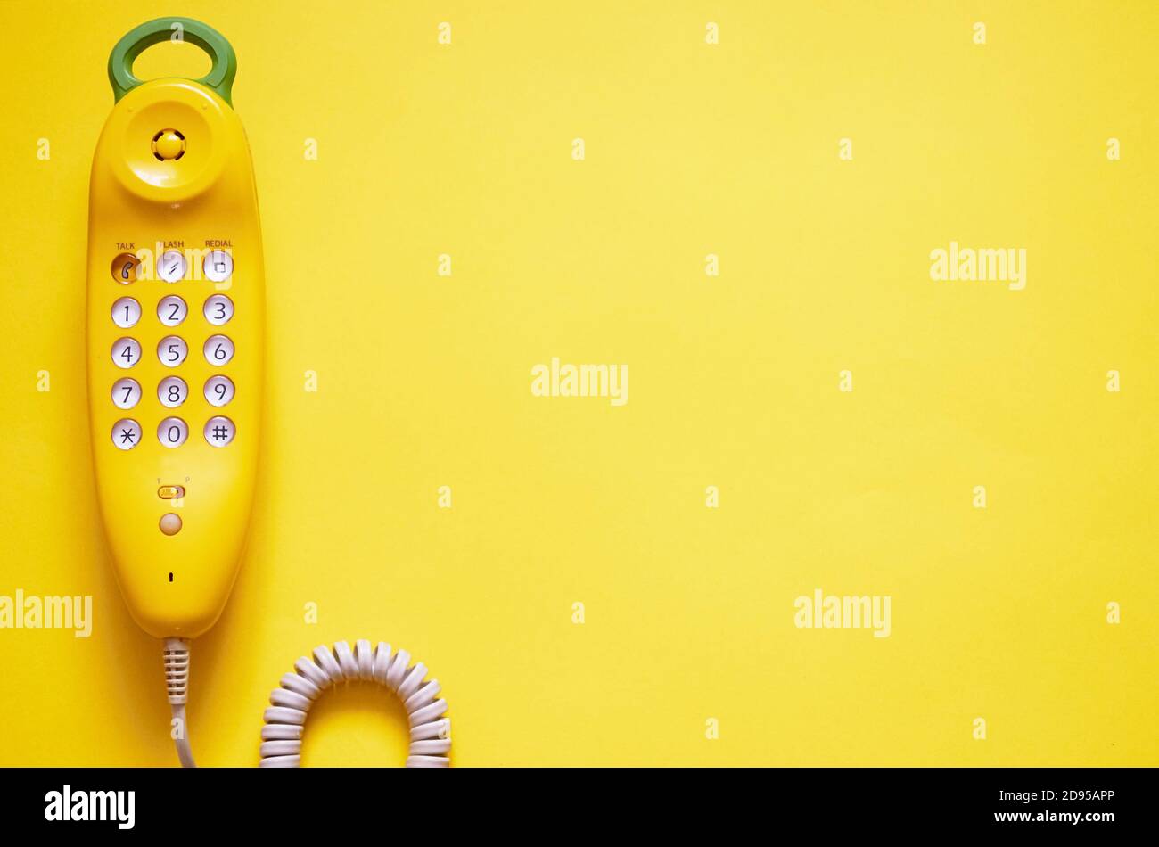 A yellow telephone receiver with a wire lies on a yellow background ...