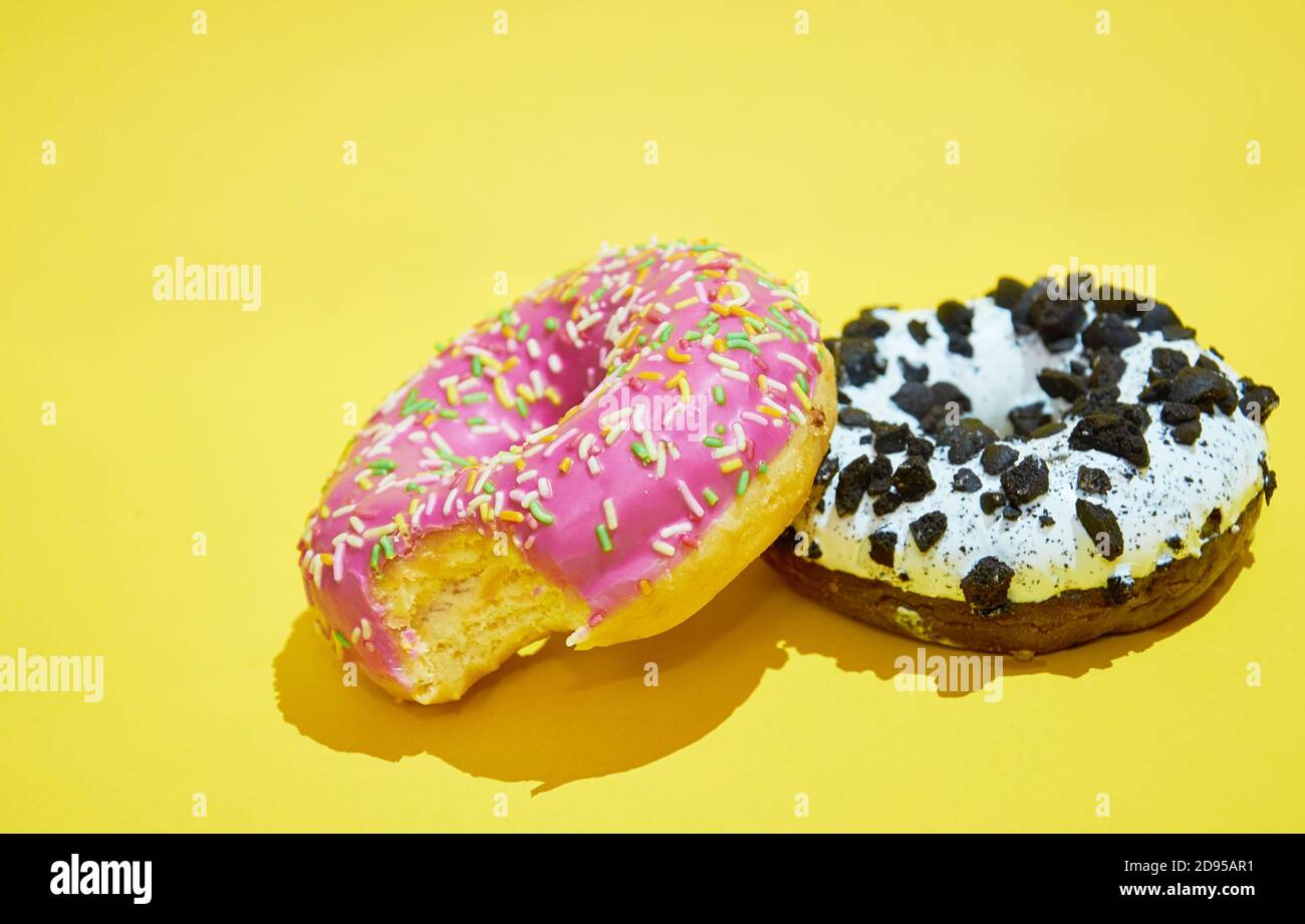 Pink and white donuts lie on a yellow background. Side view Stock Photo ...