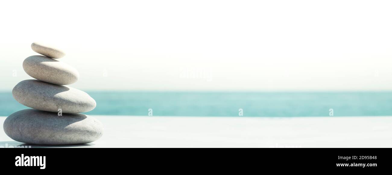 Zen relax banner background. A pyramid of stones on the beach in clear ...
