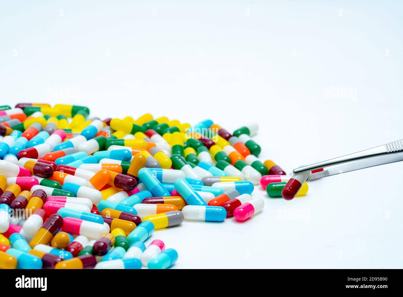Forceps pick red-white capsule from group of capsule pills. Drugs ...