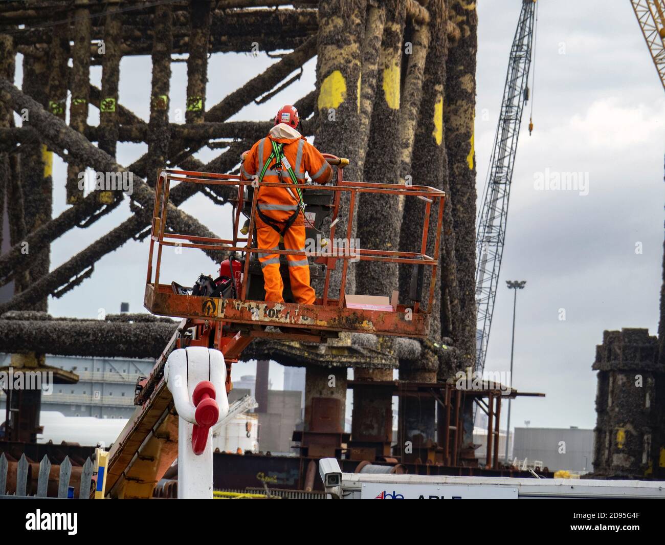 A workman on an hydraulic man hoist by an offshore platform platform ...