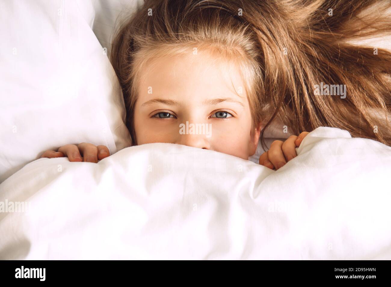 Child hiding under duvet in bed. Morning routine. Indulge in the ...