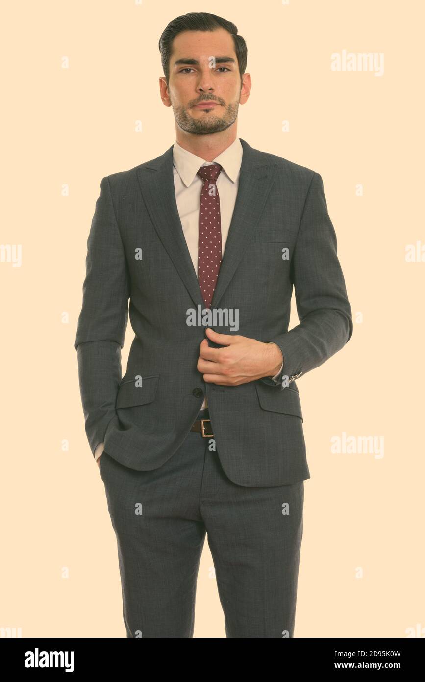 Studio shot of young handsome businessman standing while fixing suit ...