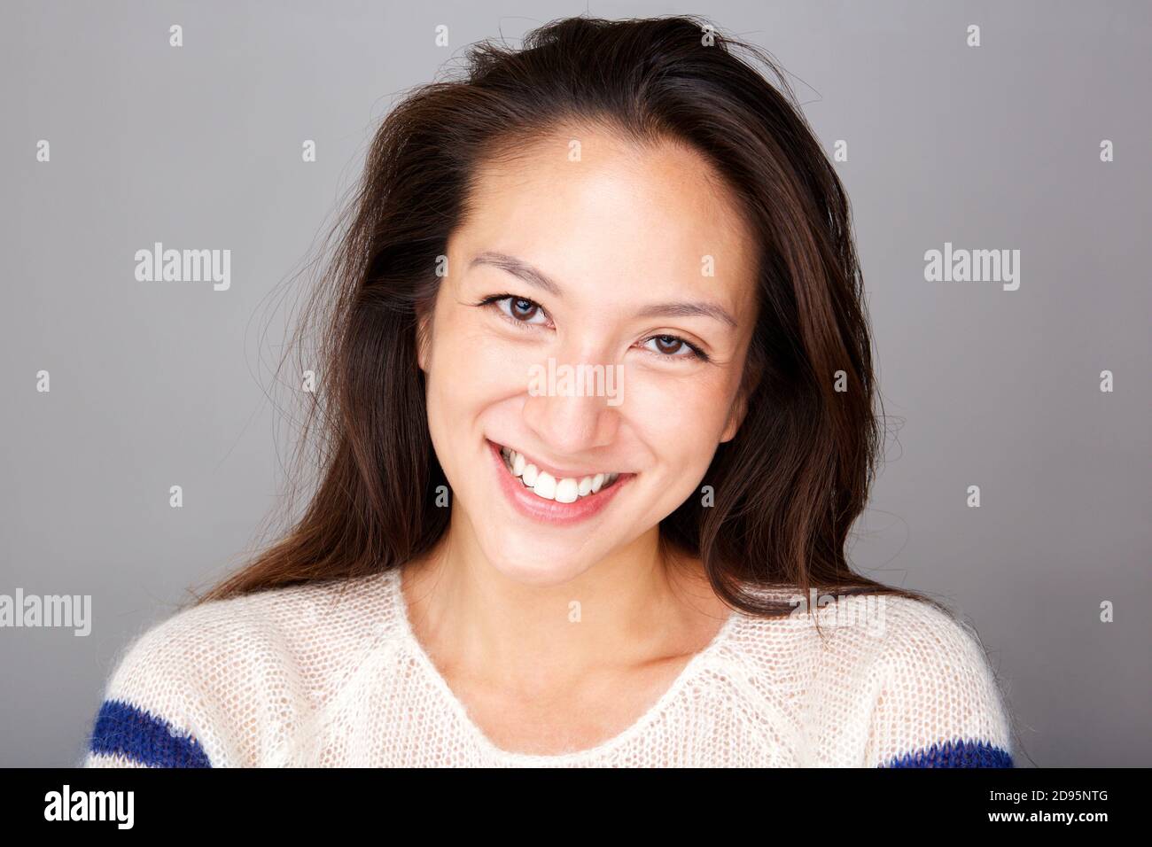 Close up front face portrait of smiling young asian woman against gray ...