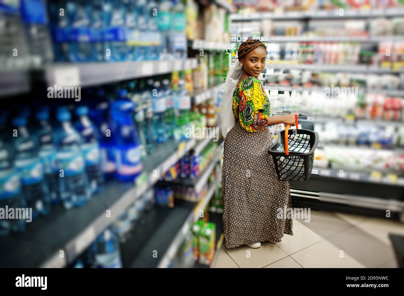 Happy african woman in traditional clothes and veil looking product at ...