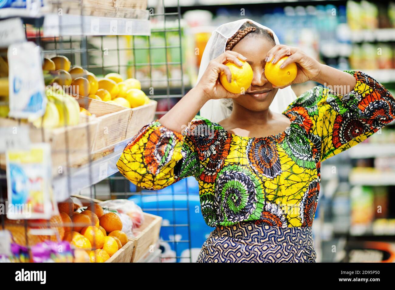Happy african woman in traditional clothes and veil looking product at ...