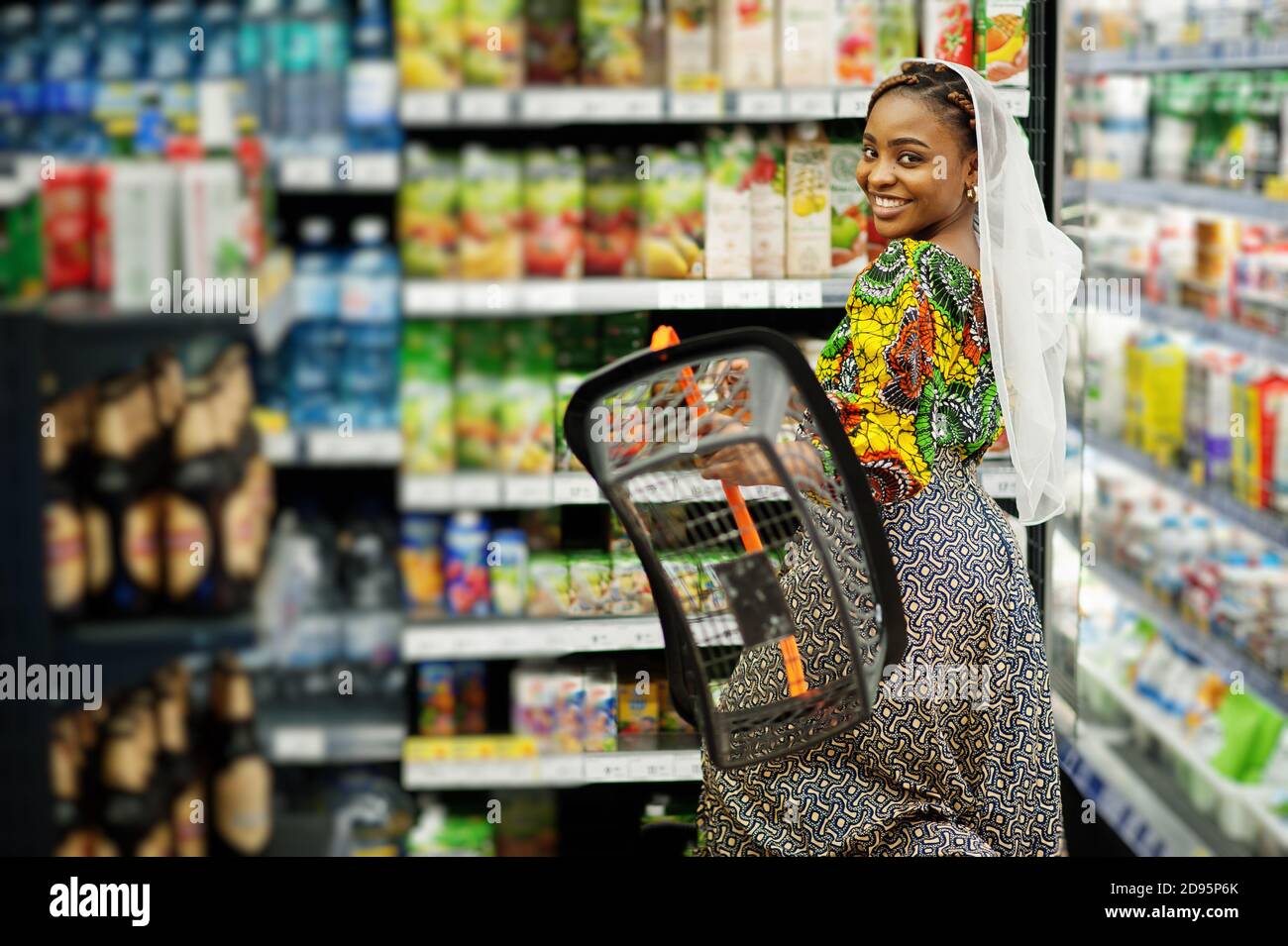 Happy african woman in traditional clothes and veil looking product at ...