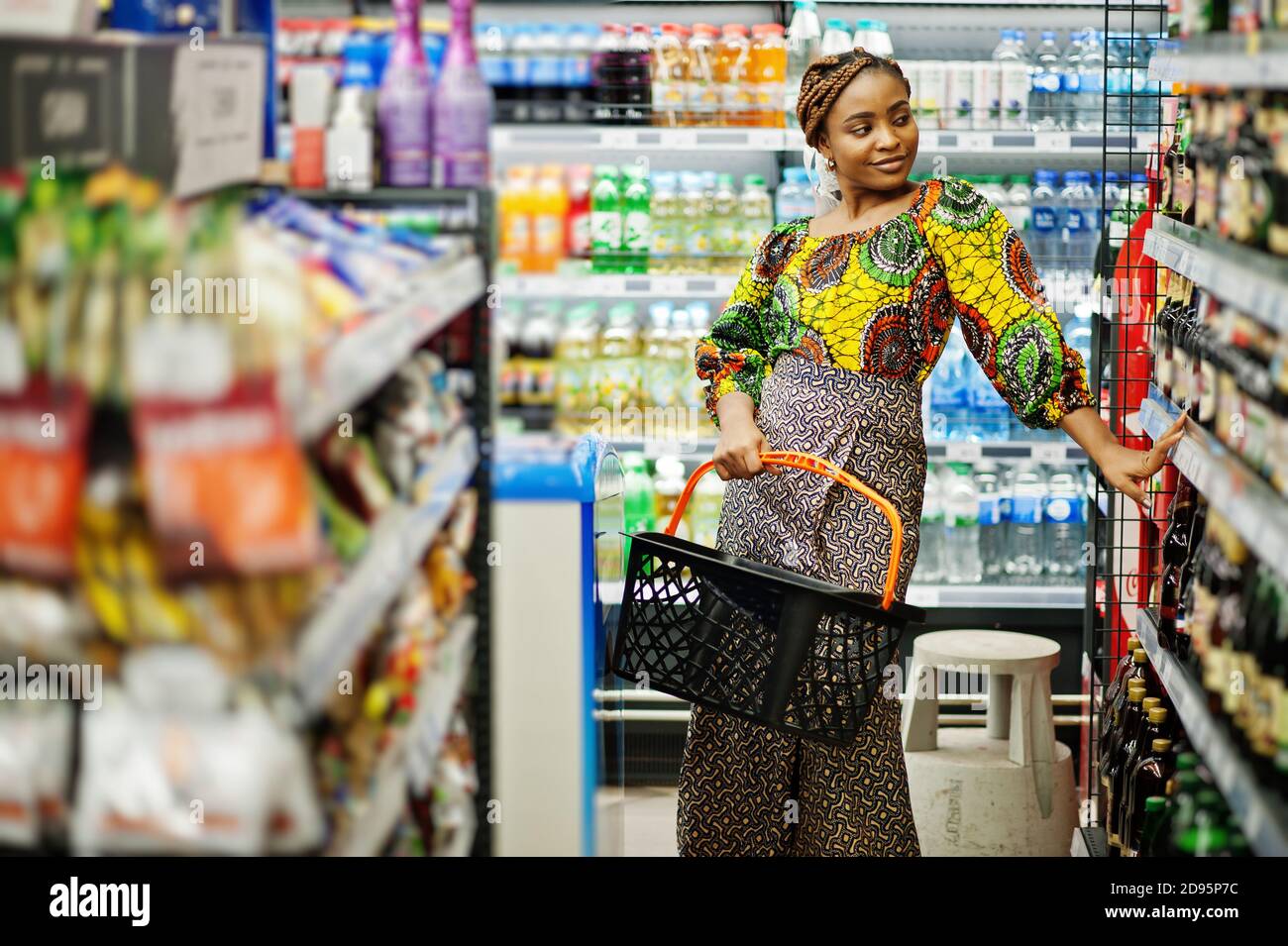 Happy african woman in traditional clothes and veil looking product at ...