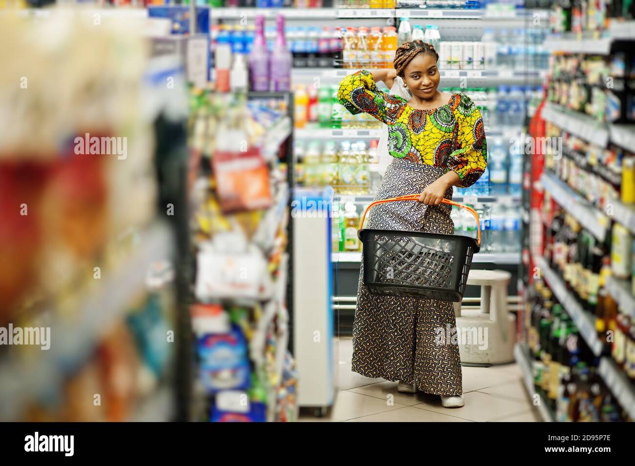Happy african woman in traditional clothes and veil looking product at ...