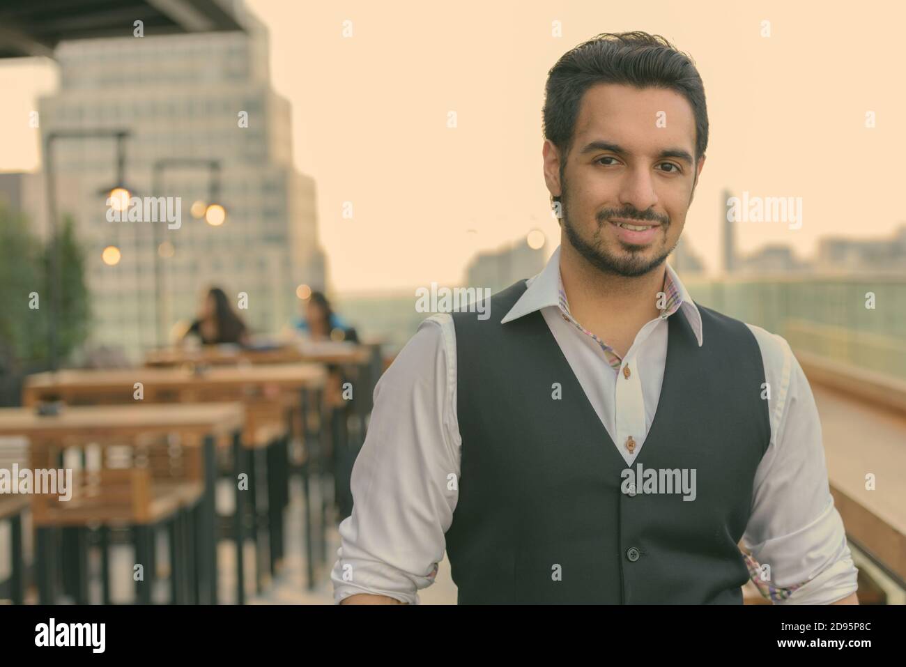 Young happy Indian man smiling at rooftop restaurant in Bangkok ...