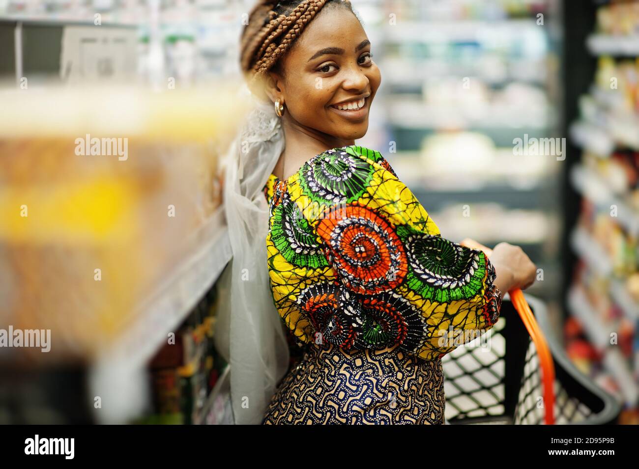 Happy african woman in traditional clothes and veil looking product at ...
