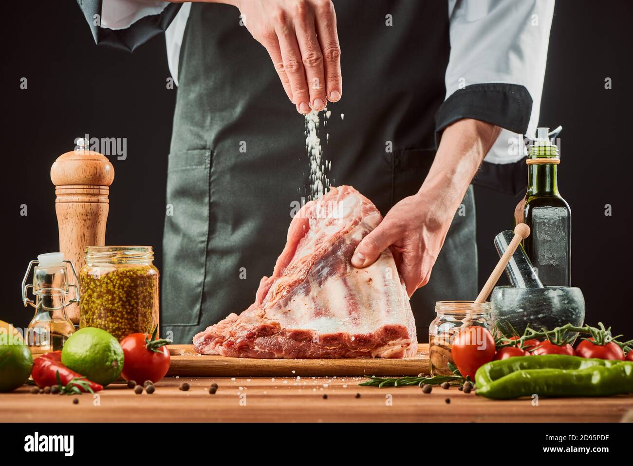 Chef throws a pinch of salt onto beef ribs Stock Photo - Alamy
