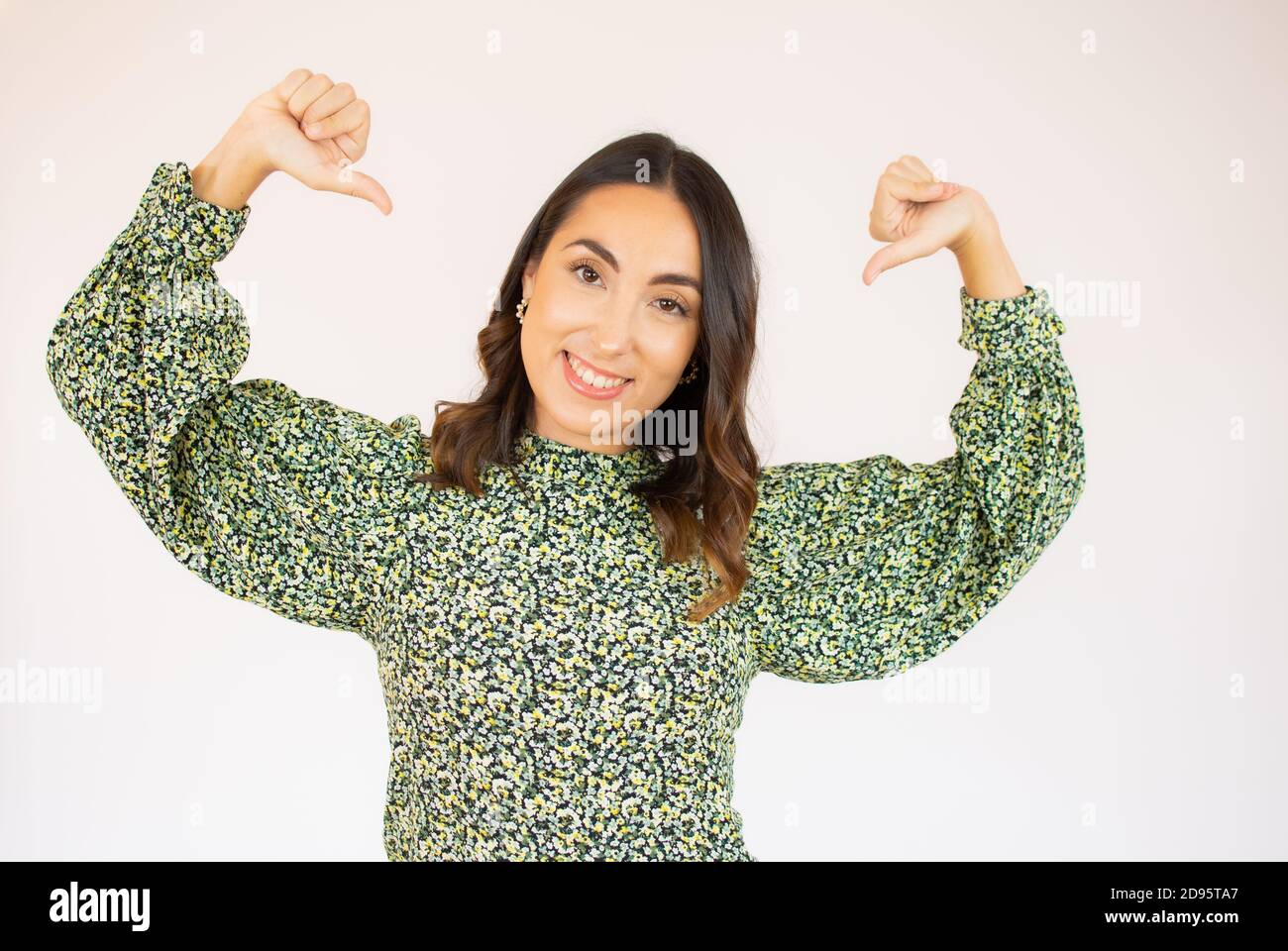 Portrait of young smiling woman pointing thumbs herself isolated over ...