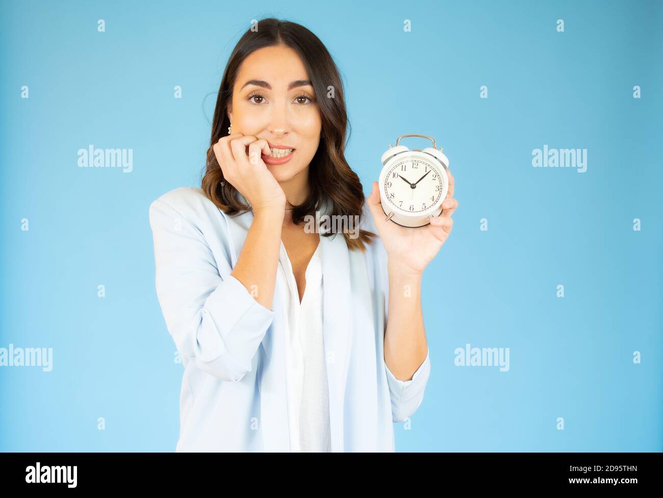 Worried cute young woman pointing at alarm clock with frustrated ...