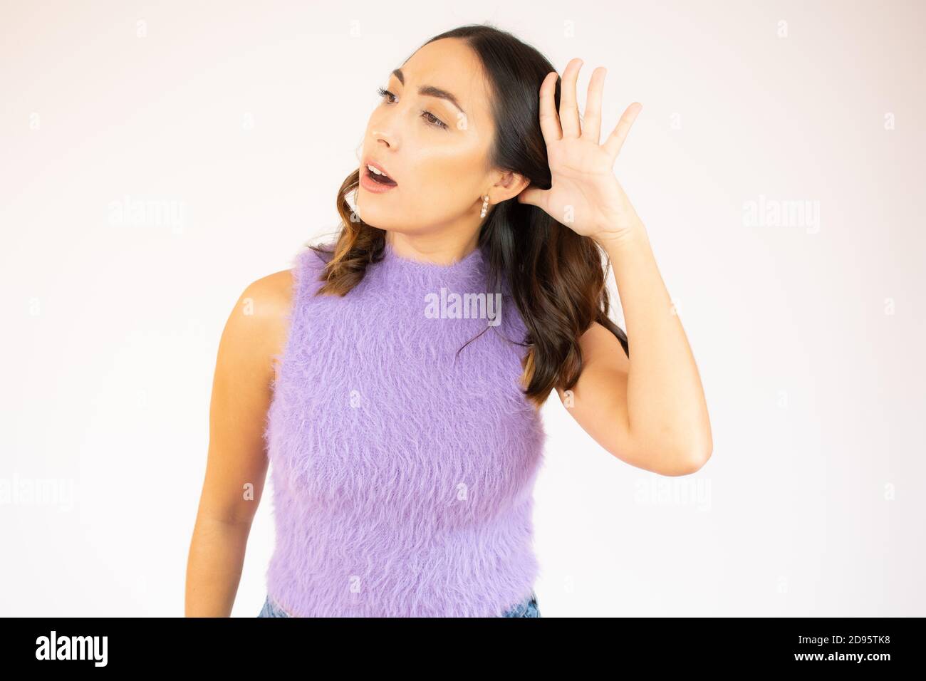 Young woman over isolated white background listening to something by ...