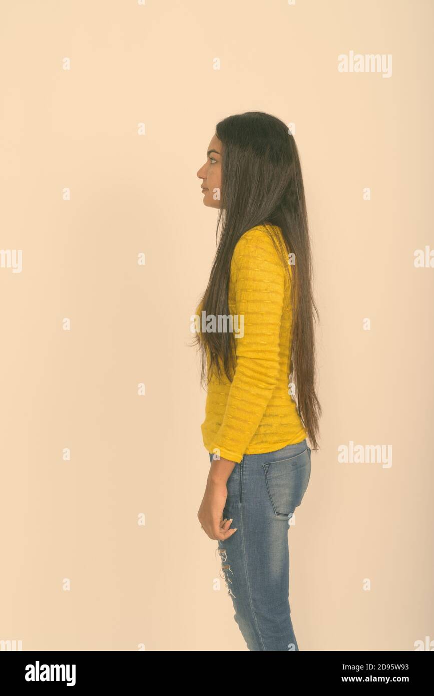 Profile view of young Indian woman standing against white background ...