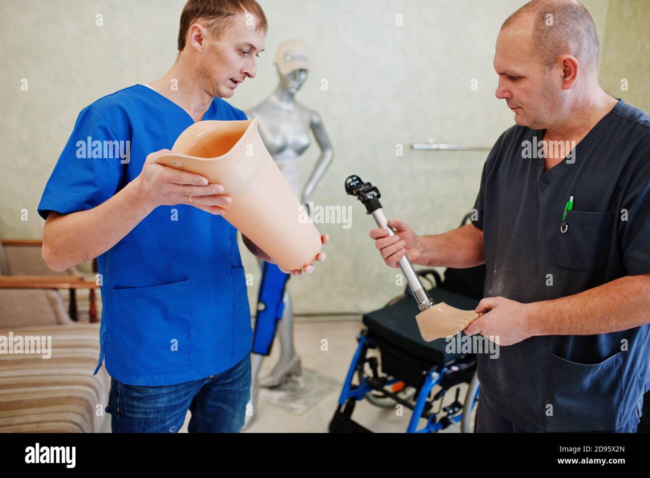 Two prosthetist man workers with prosthetic leg working in laboratory ...