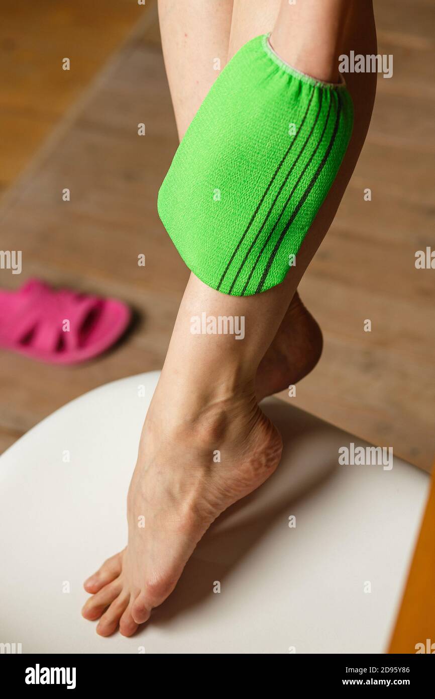 Woman massages leg with green terry washcloth with mittens Stock Photo ...