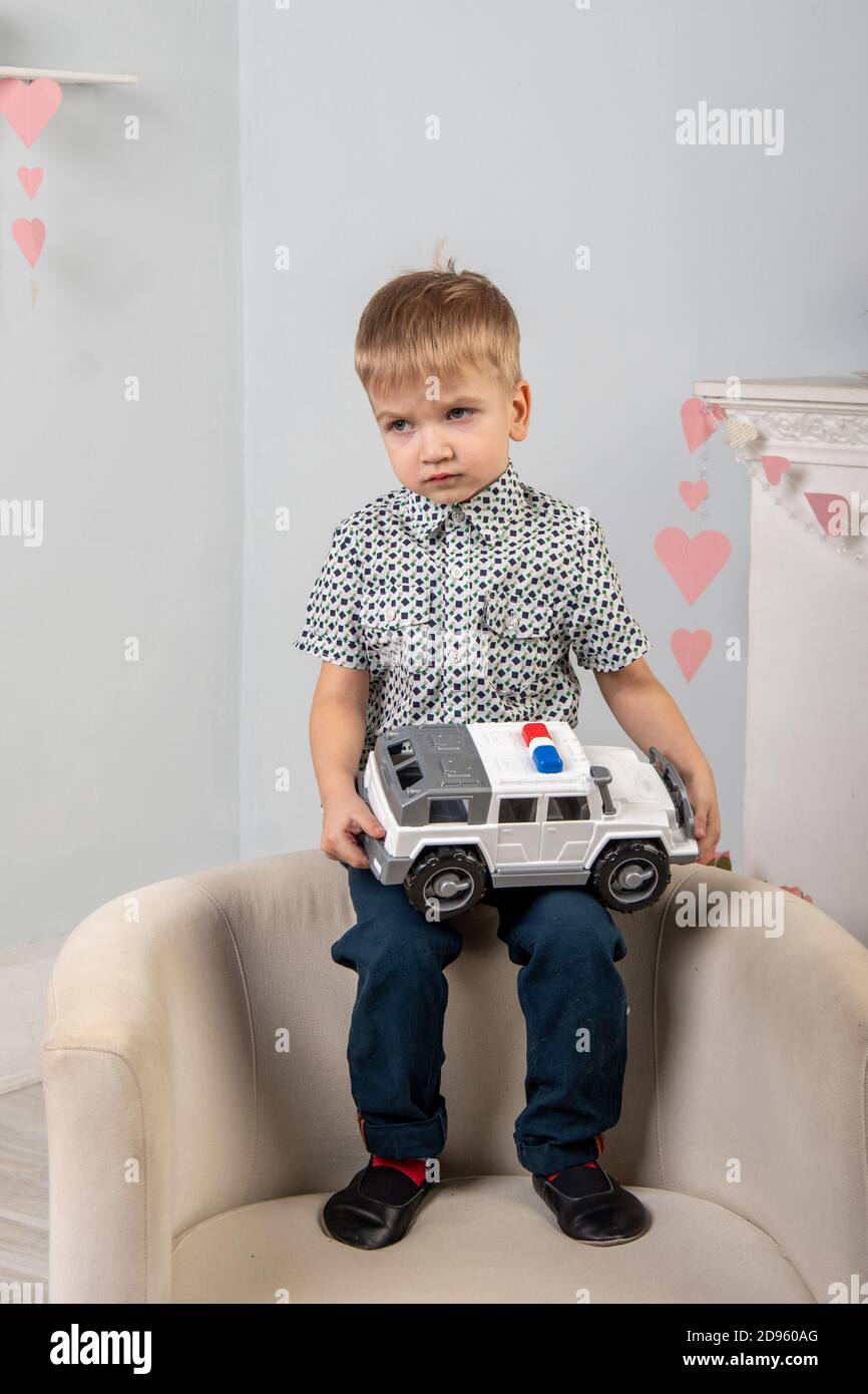 a sad boy sits on the back of a chair and holds in his hands a large ...