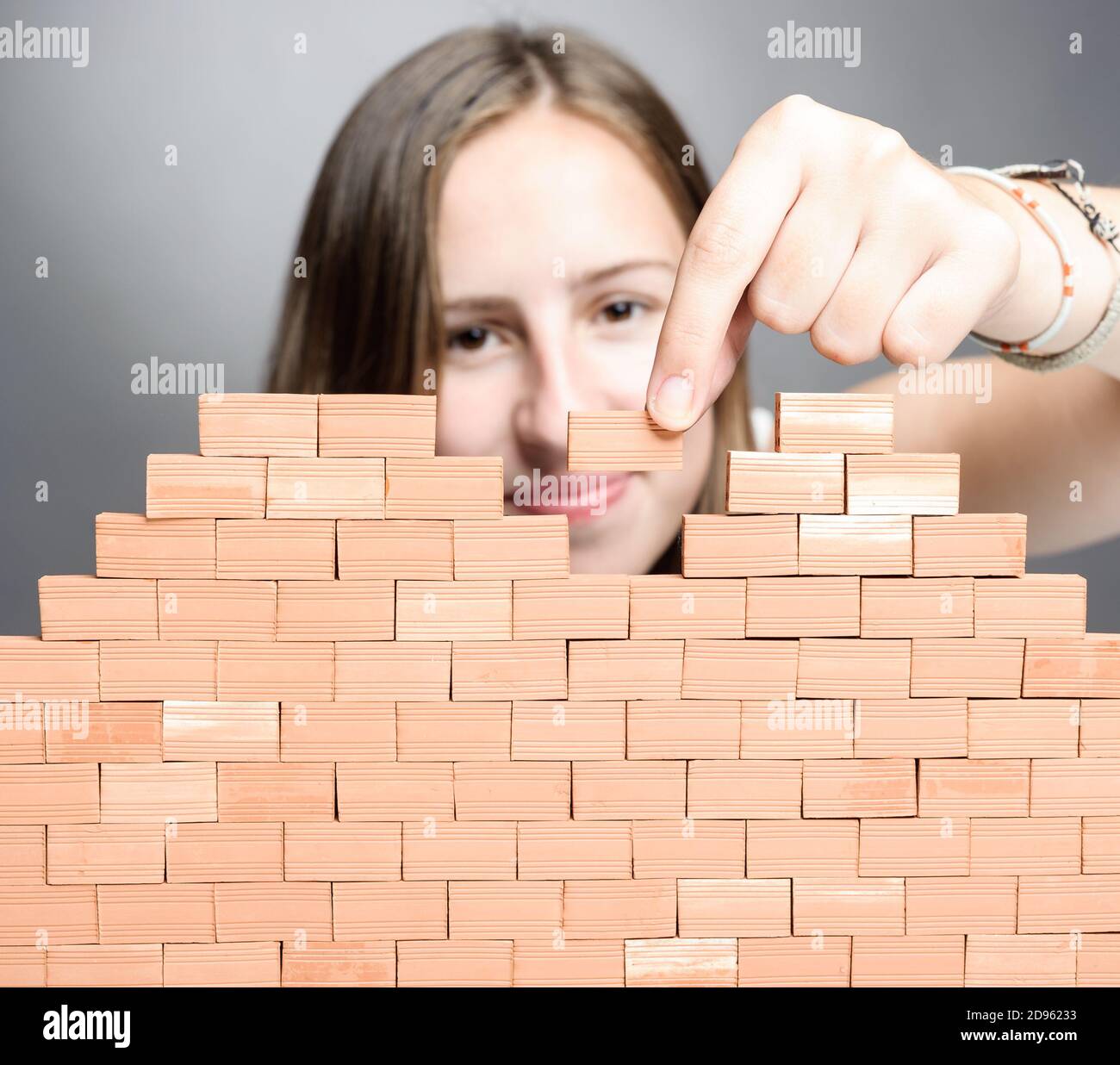 young woman building a wall on a grey background Stock Photo - Alamy