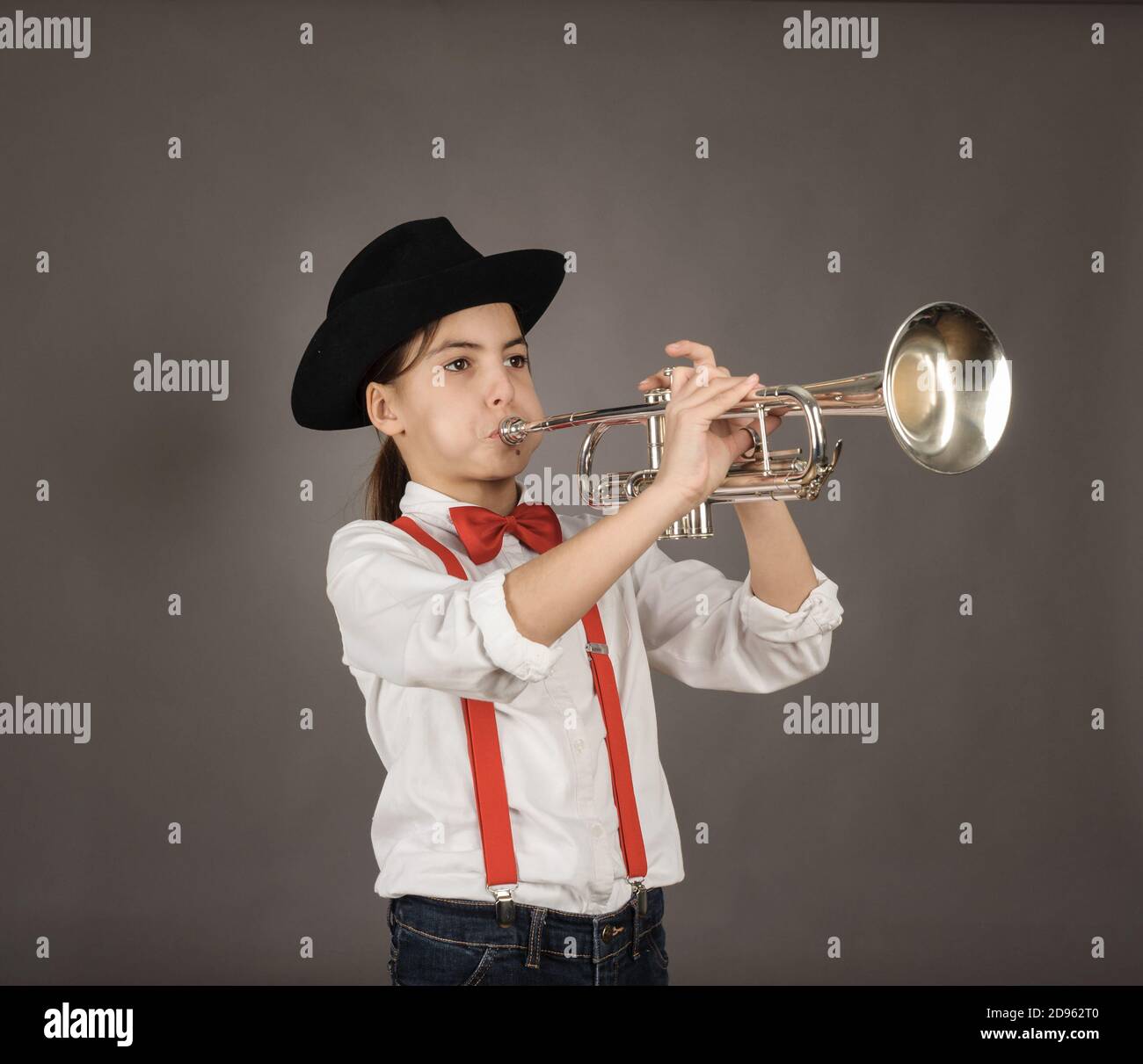 little girl playing trumpet on a gray background Stock Photo - Alamy