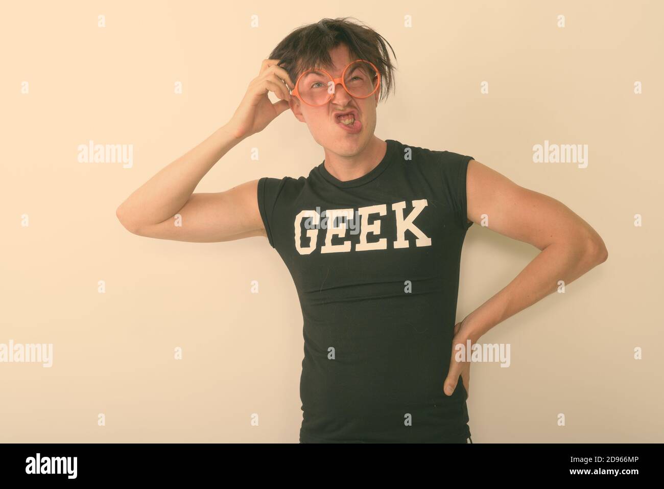 Studio shot of young nerd man looking confused while scratching head ...