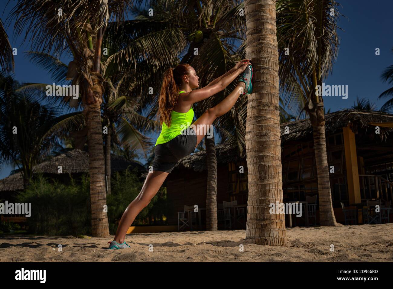 Young woman is doing splits next to a palm tree on a beach Stock Photo ...