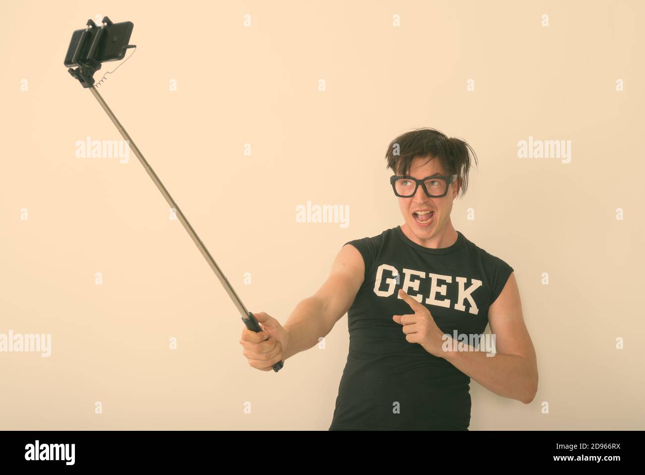 Happy young nerd man taking selfie with phone on selfie stick and ...