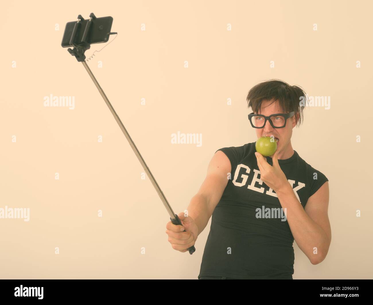 Happy young nerd man taking selfie with phone on selfie stick and ...