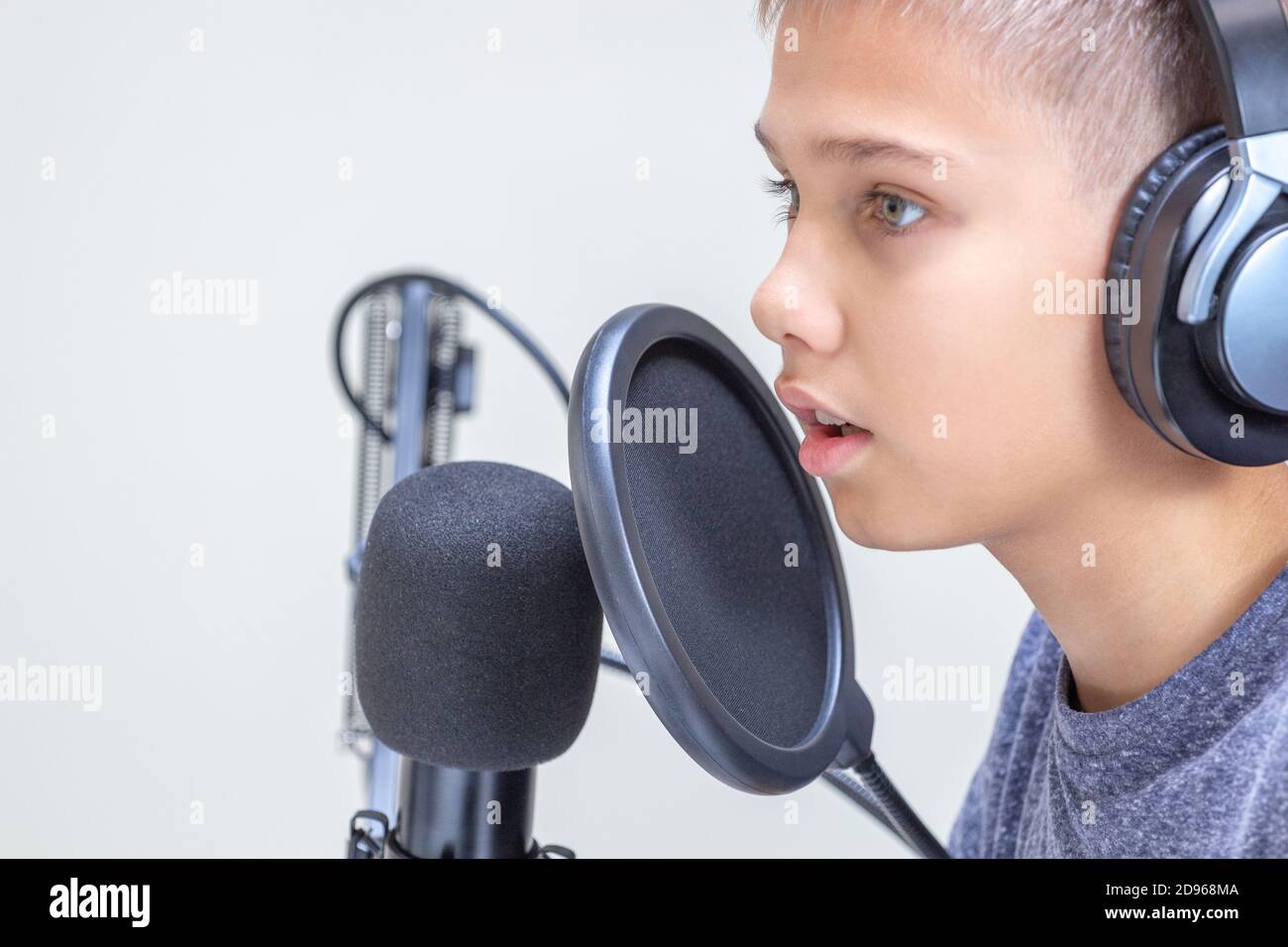 Portrait of teenage boy wearing headphones using microphone. Online ...