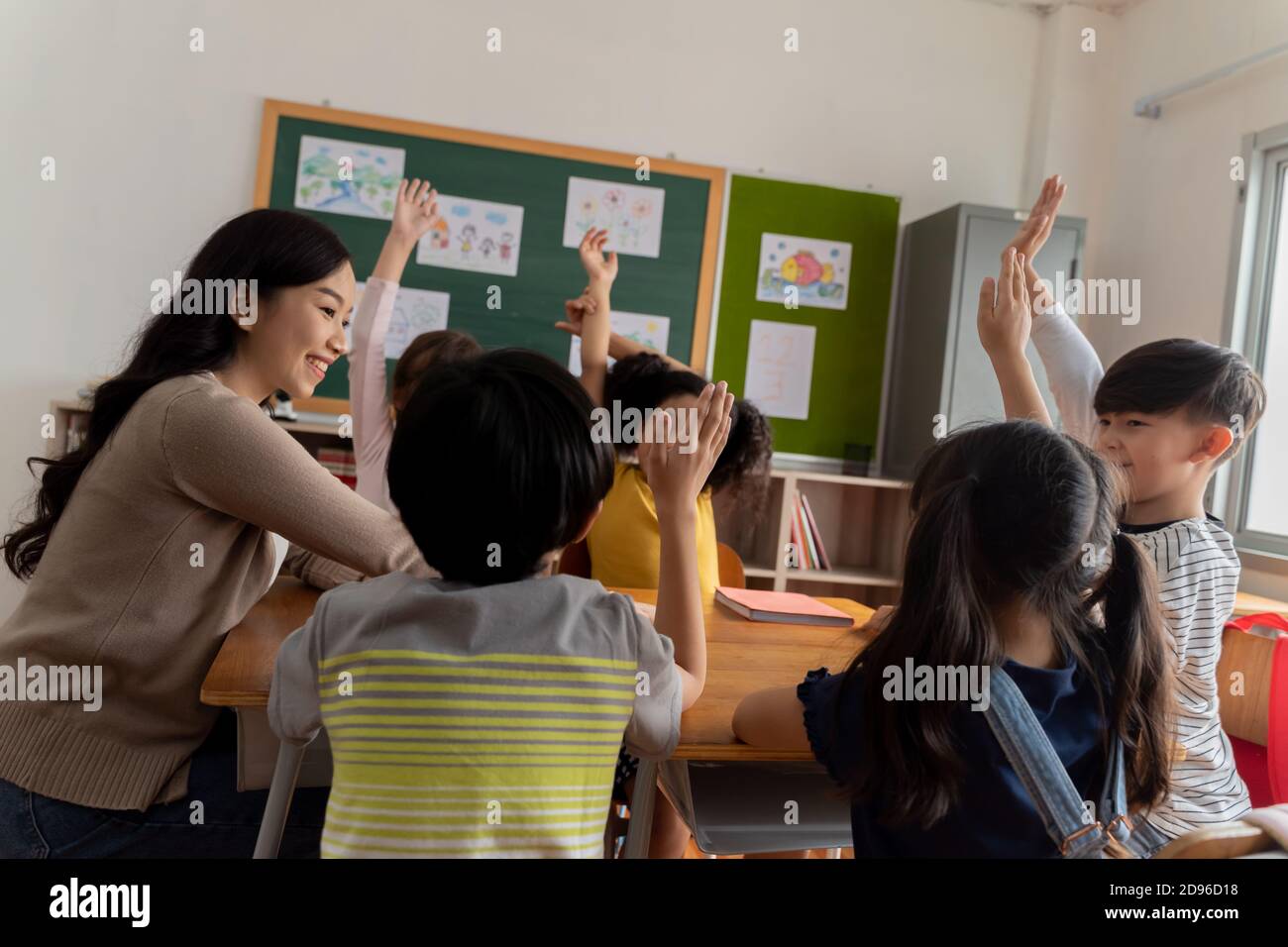 Primary school children raising hands in class hi-res stock photography ...