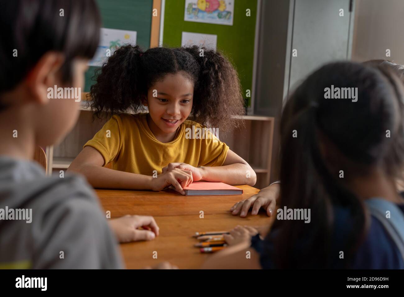Serious African American school girl looking at children in classroom ...